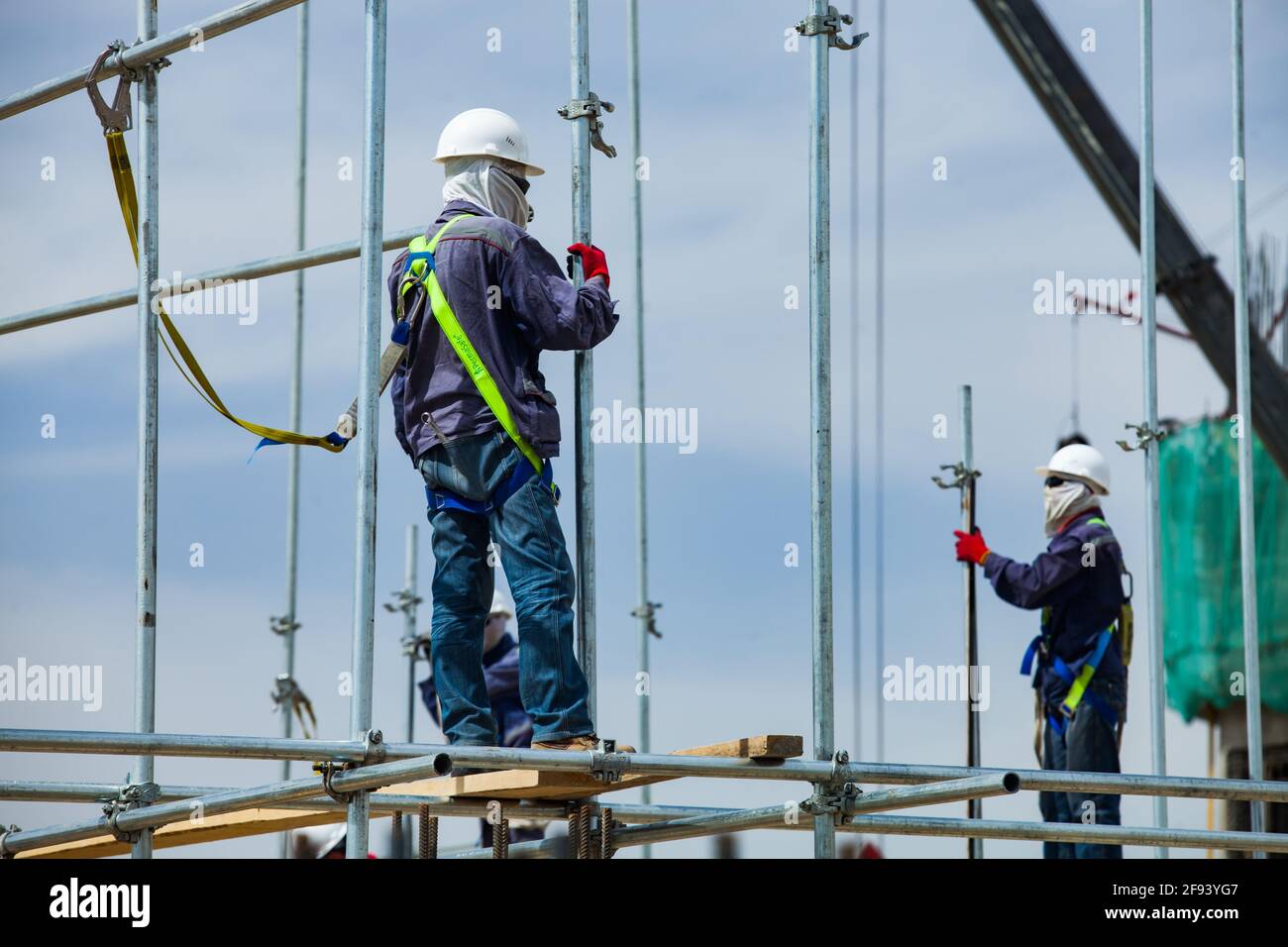 Industrial climbers assembling construction scaffolding in sunny day ...