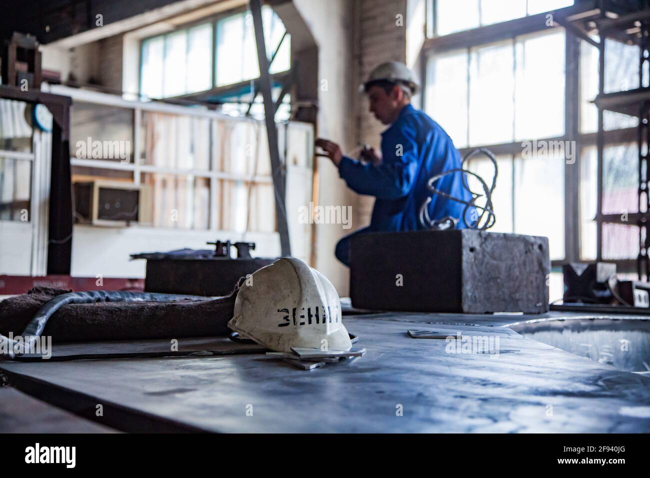 Manufacturing plant workshop. White hard hat in focus on foreground ...
