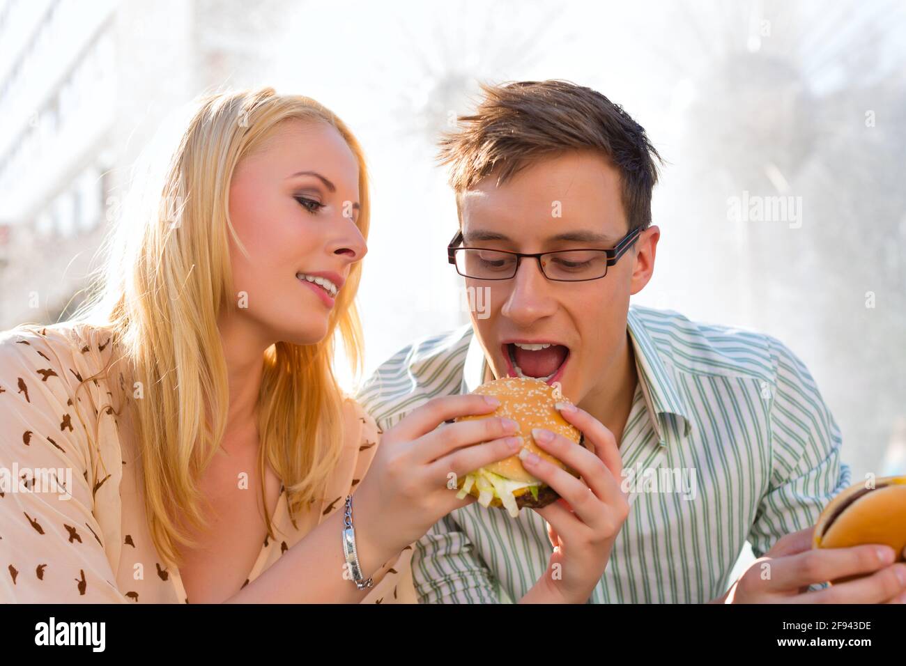 Two people sitting eating burgers hi-res stock photography and images ...