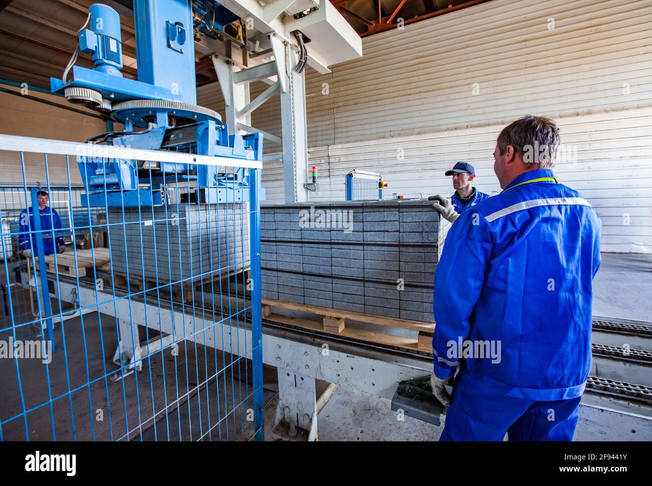 Paving tile production machine. Workers on ready tiles packing line ...