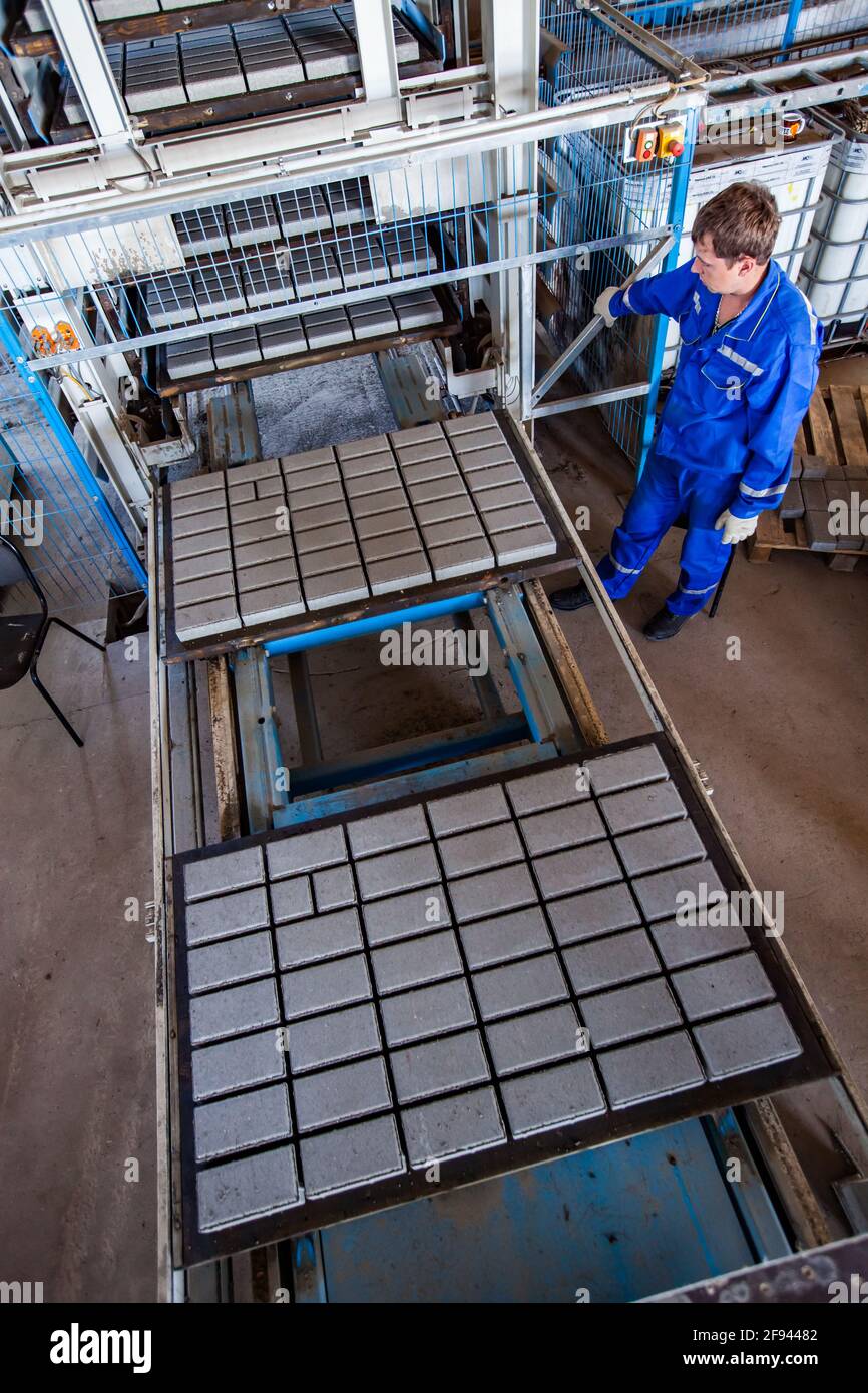 Paving tile production machine. Worker on packing line.Making stack of ...