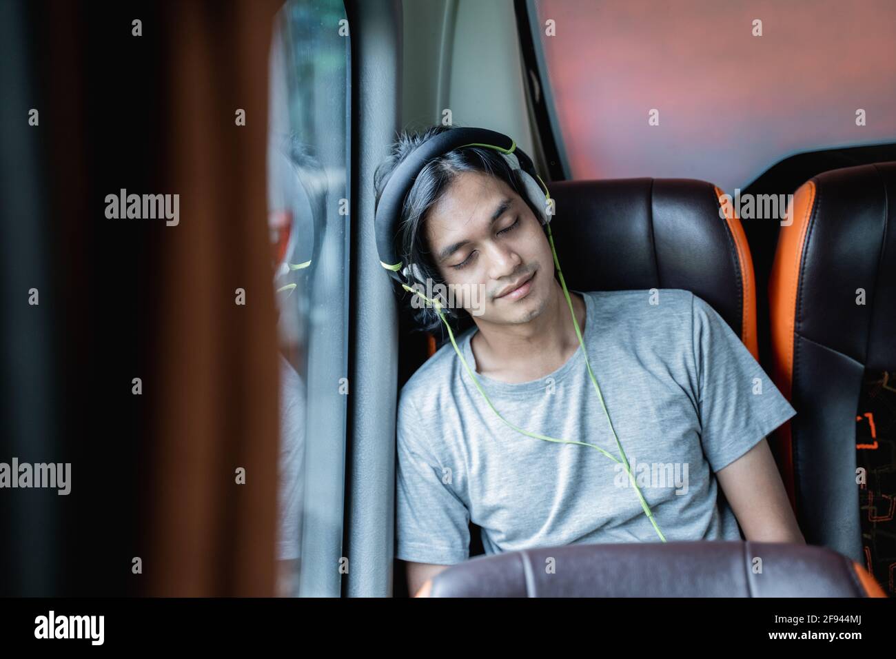 a young man wearing sleep headphones is leaning against the window ...