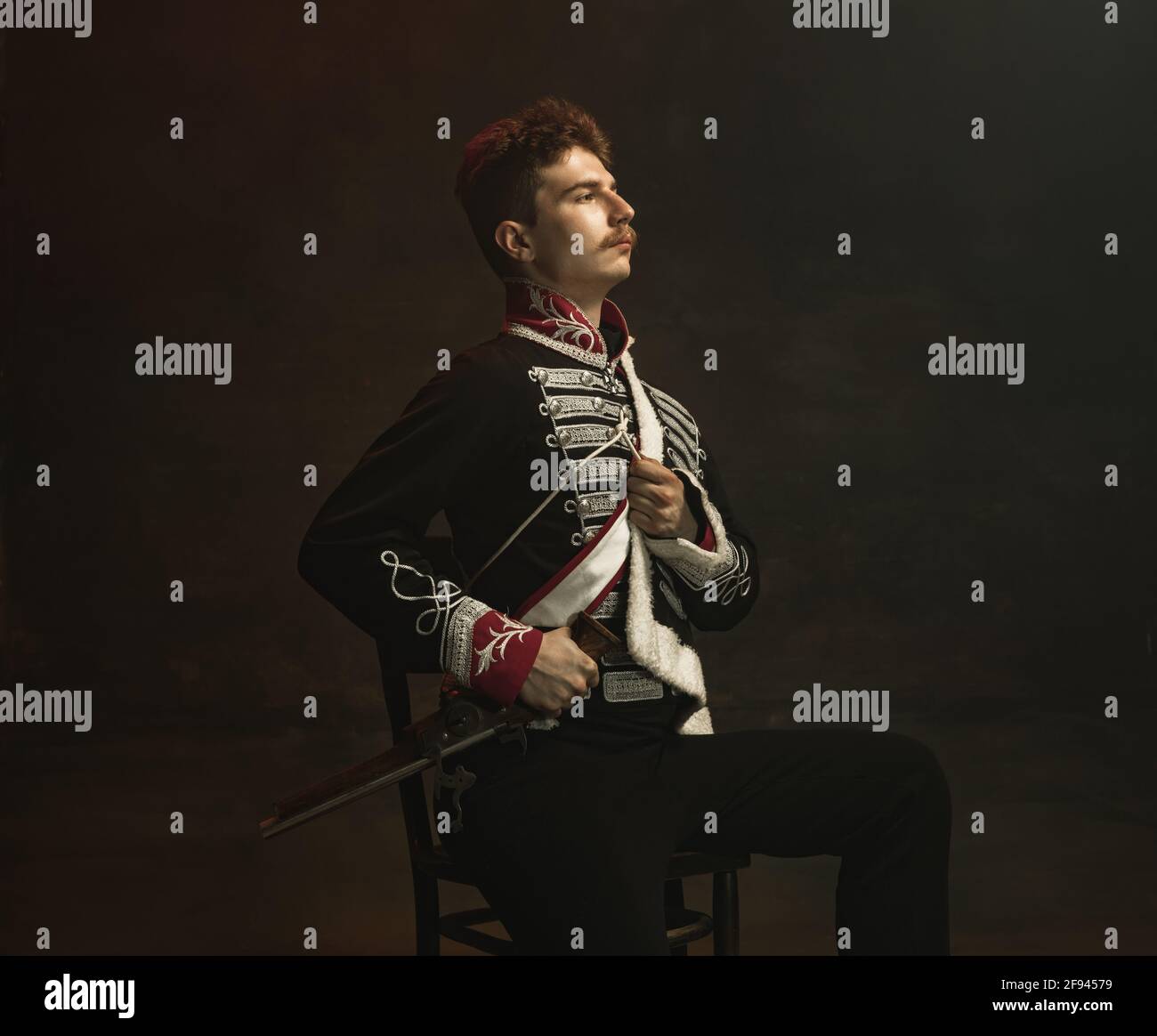 Young man in suit as royal person isolated on dark green background ...