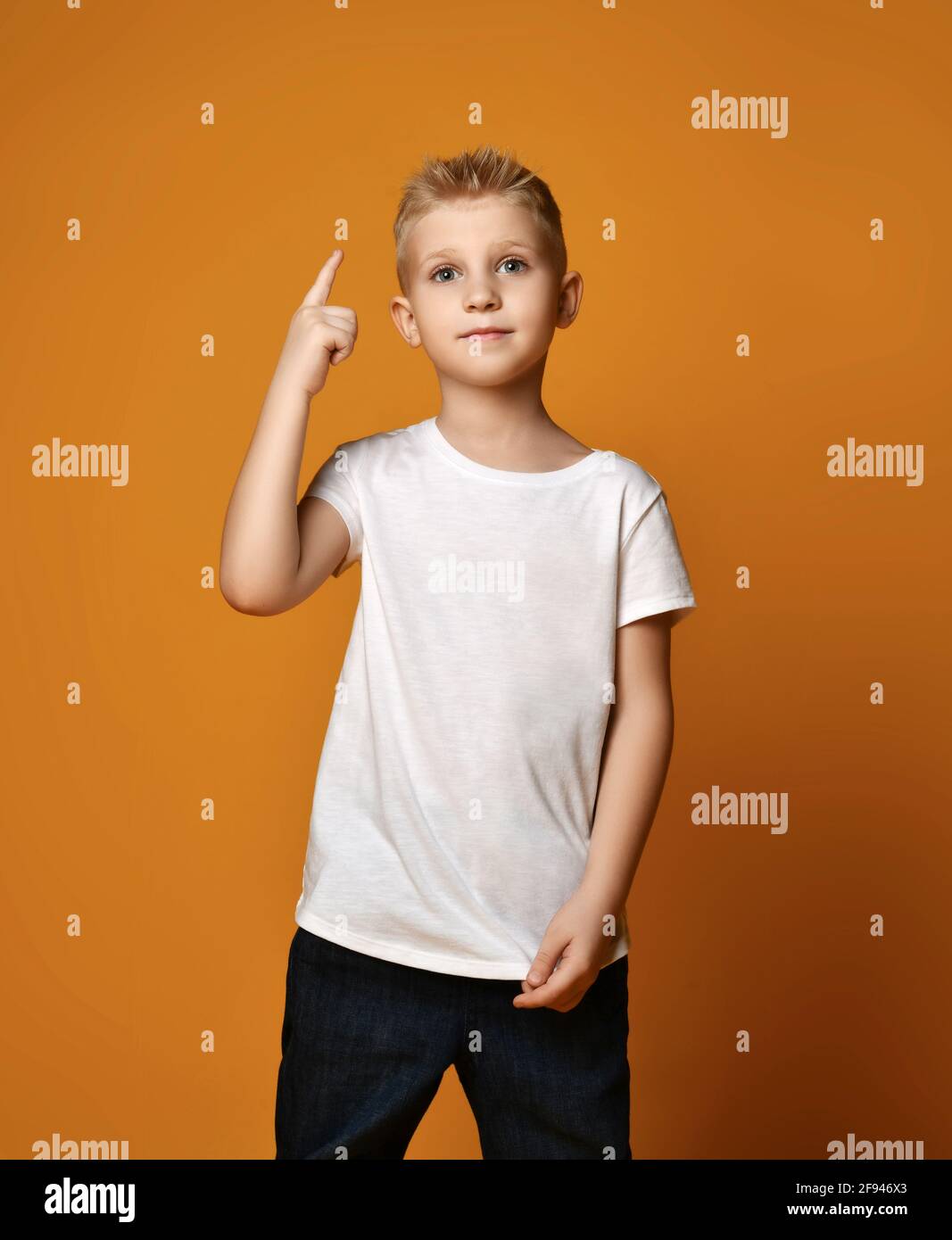 Young school boy kid in white t-shirt pointing forefinger up or number ...