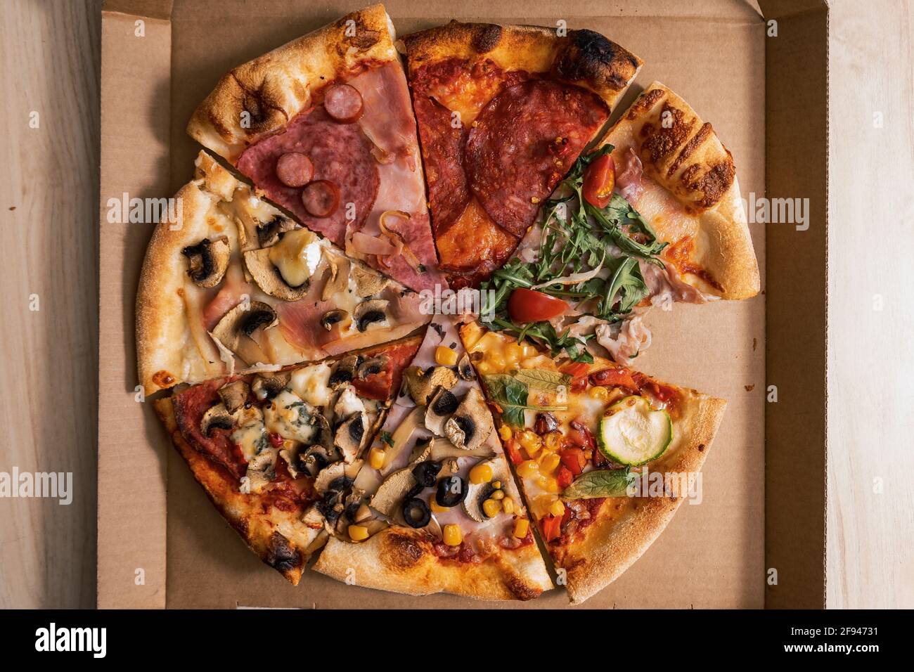Top view of slices of pizza with different toppings in a cardboard box ...