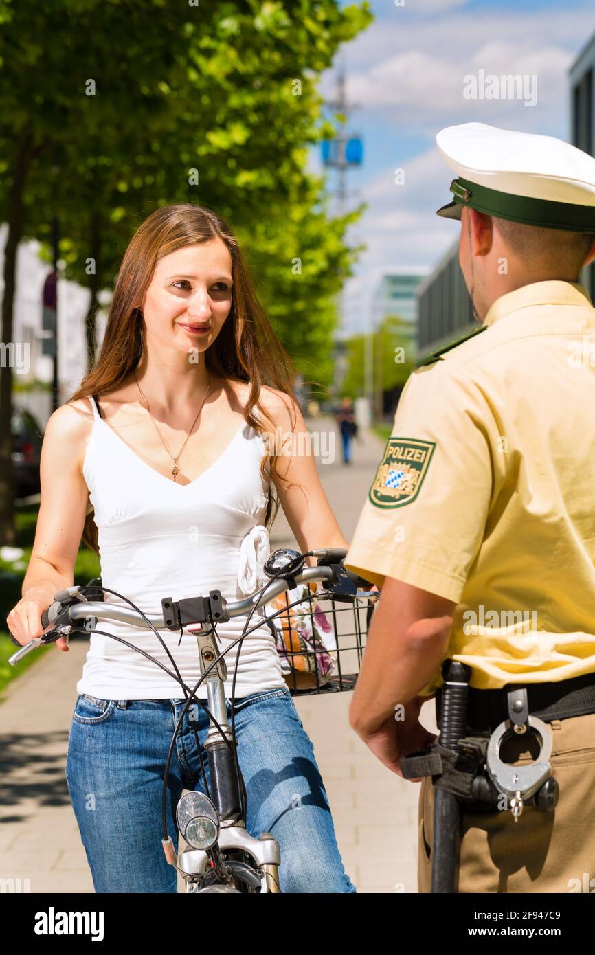 Police - young woman on bicycle with police officer in traffic control ...