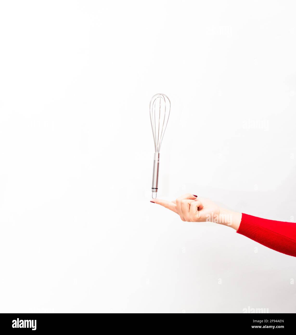 The finger of a woman's hand balances a metal whisk for cooking Stock ...