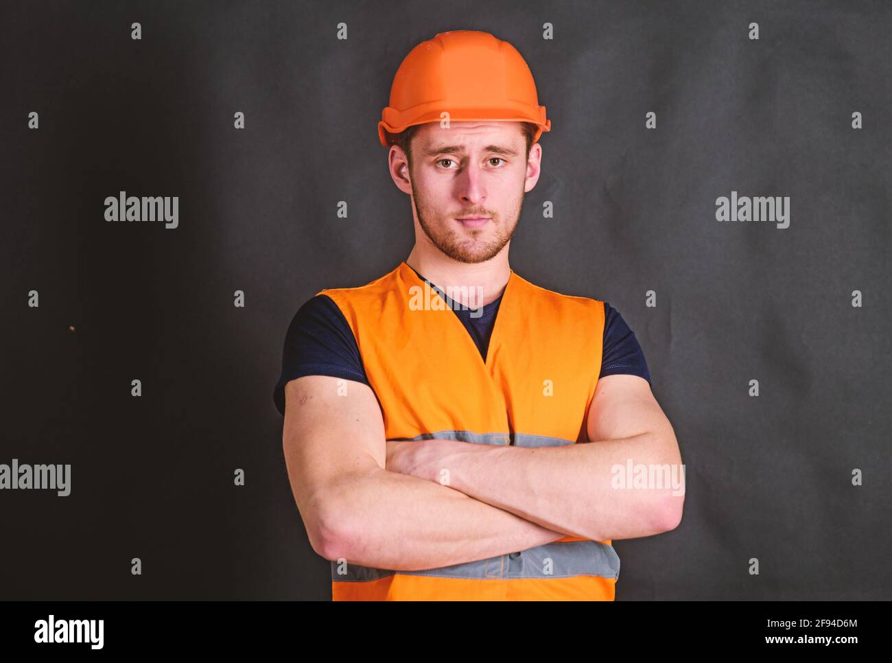 Man in helmet, hard hat hold arms crossed on chest, black background ...