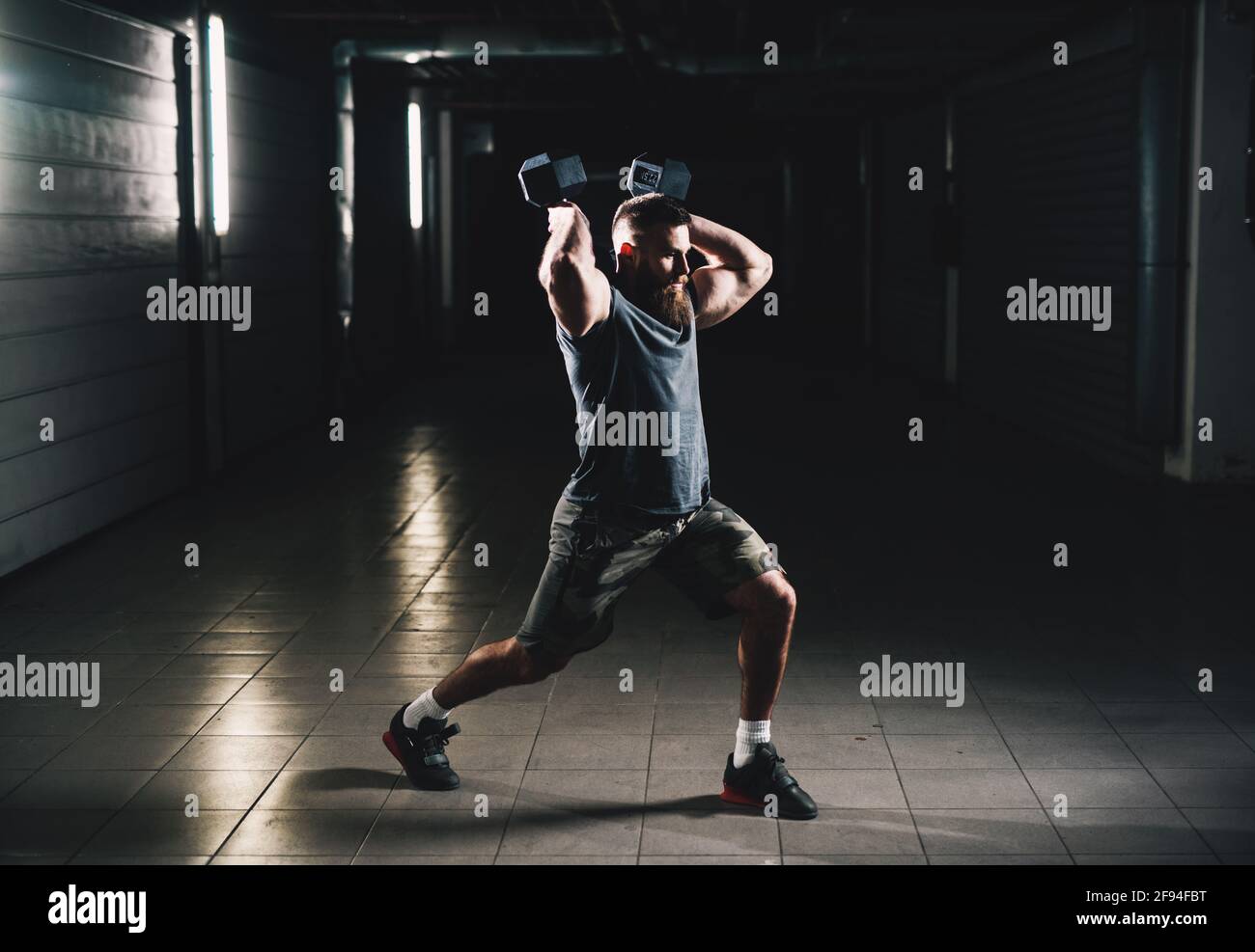 Powerfully motivated strong bodybuilder guy holding a heavy dumbbells ...