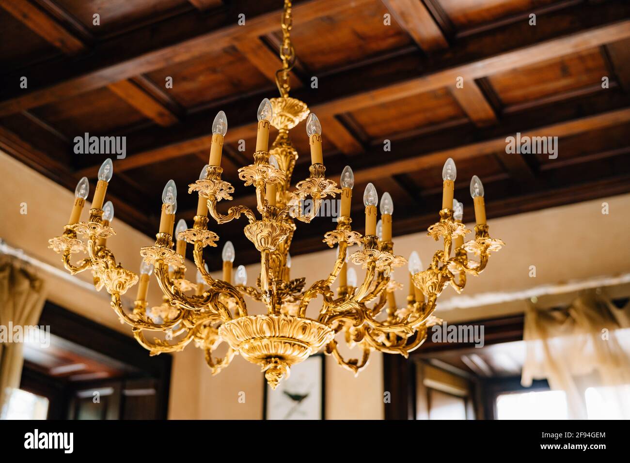 Gold chandelier with candle light bulbs on the ceiling Stock Photo - Alamy