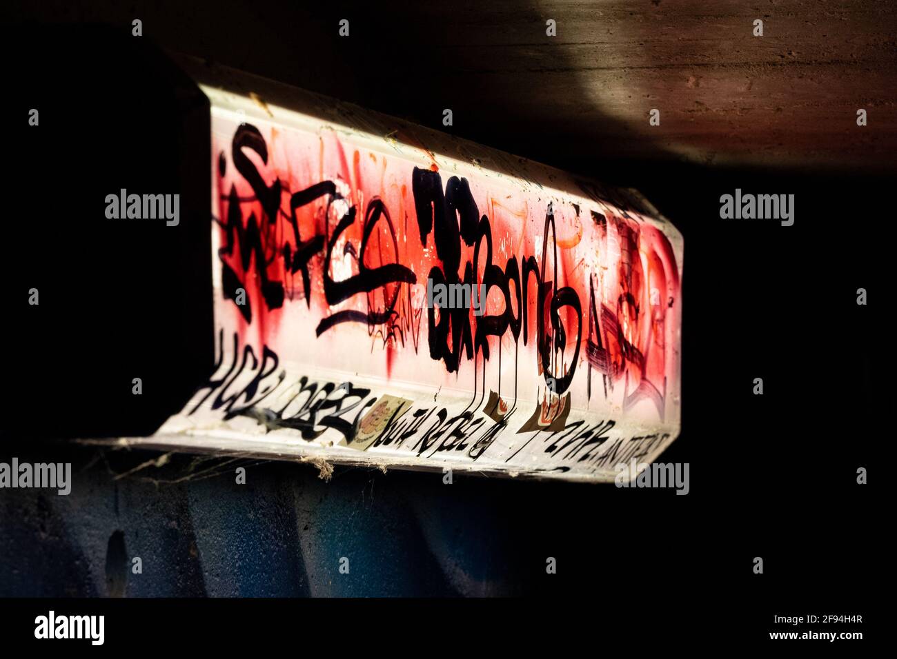 Closeup of a street sign defaced with graffiti in a dark tunnel Stock ...