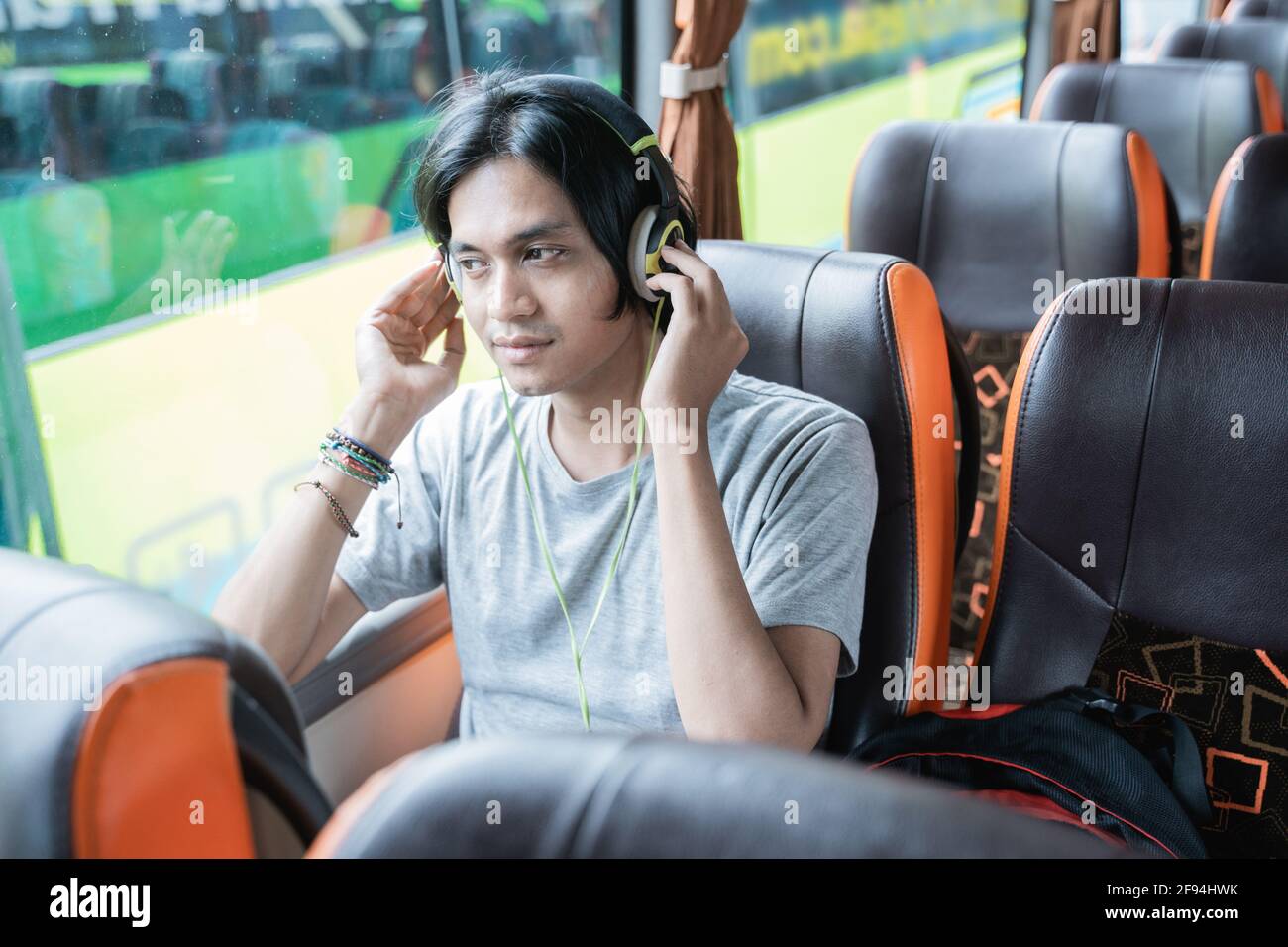 a young man wearing headphones while listening music from a handphone ...