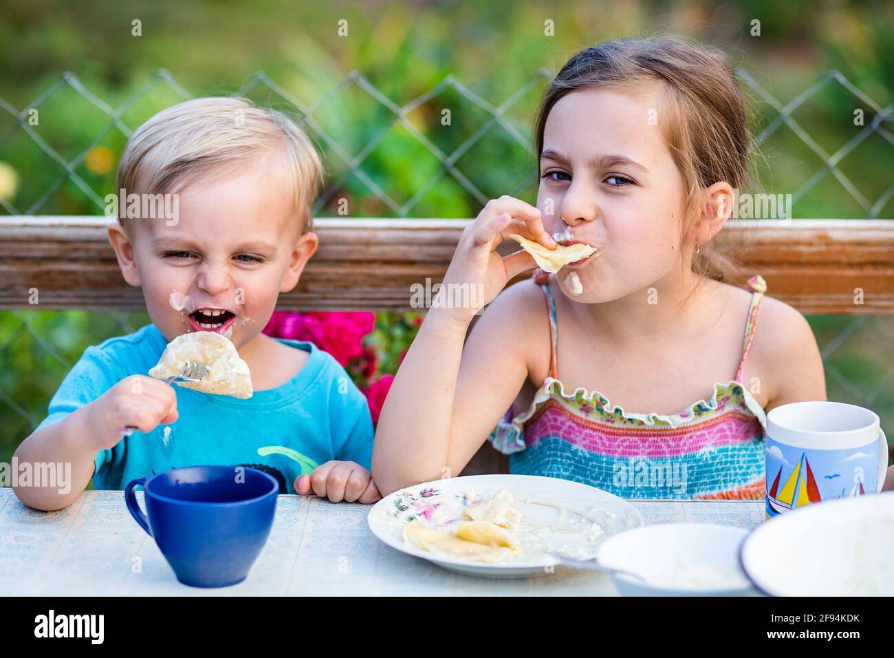 Funny boy and girl eating dumplings and making a mess Stock Photo - Alamy