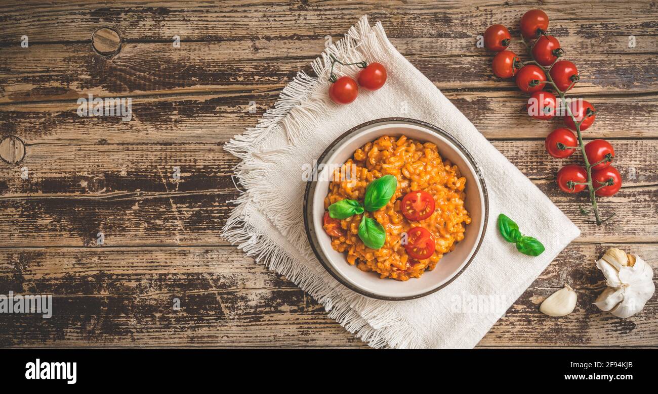 Homemade tomato risotto with fresh basil on a rustic wooden table, top ...