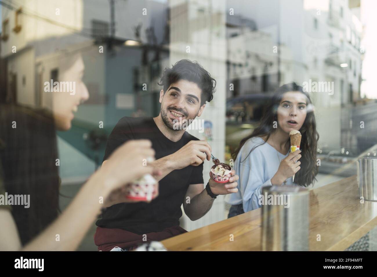Friends eating ice cream in a cafe behind a window Stock Photo - Alamy