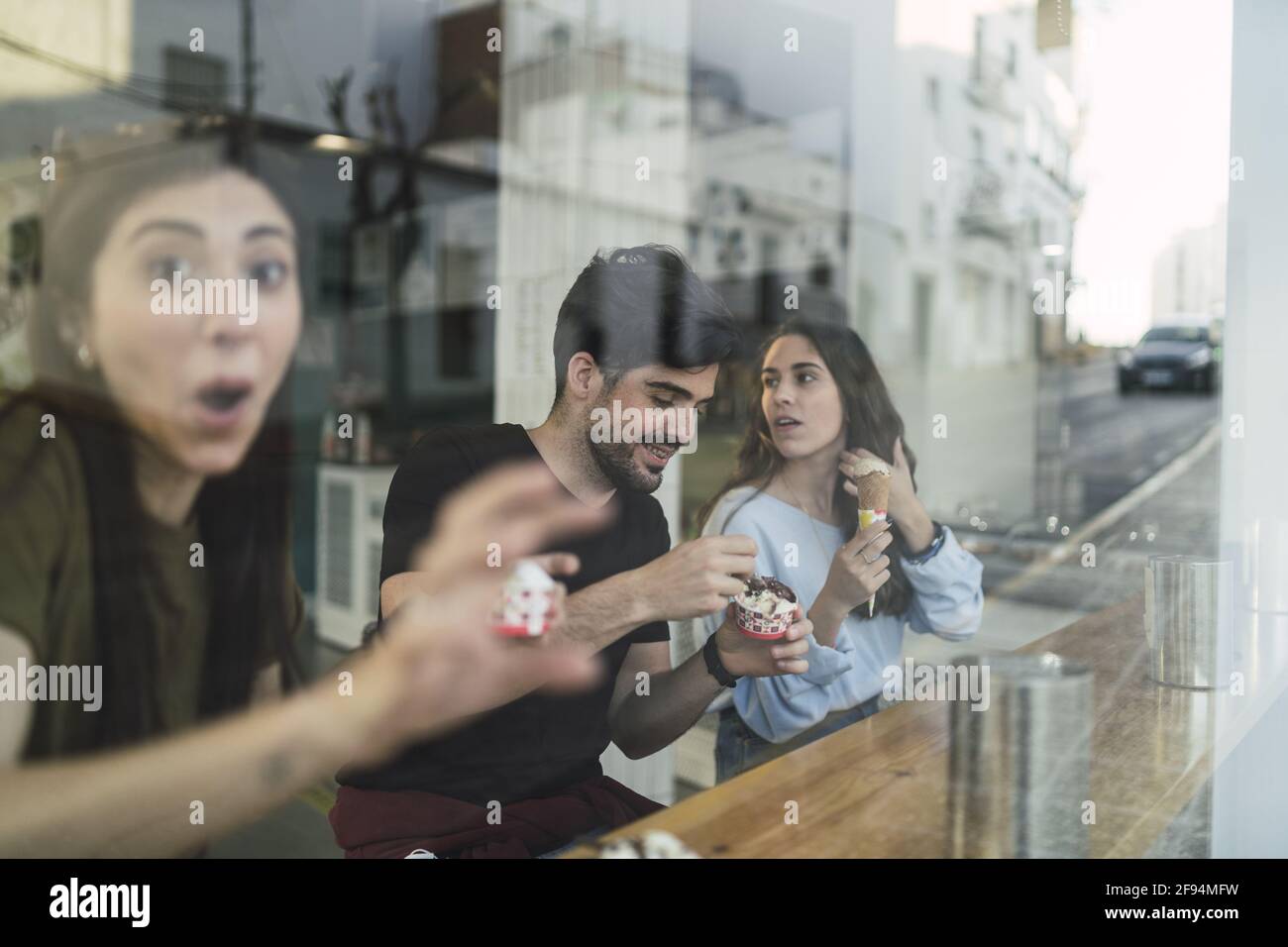Friends eating ice cream in a cafe behind a window Stock Photo - Alamy