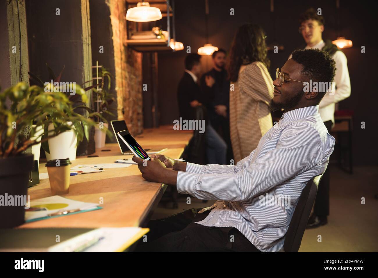 Colleagues working together in modern office using devices and gadgets ...