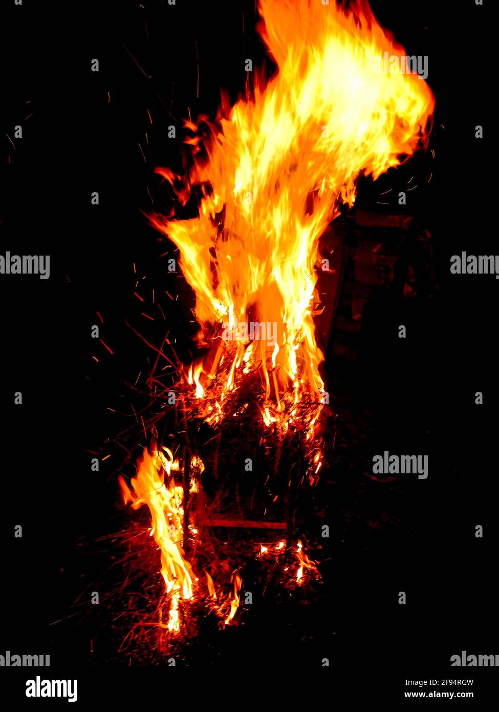 Closeup of the yellow fire flames from the burning wood in the dark ...