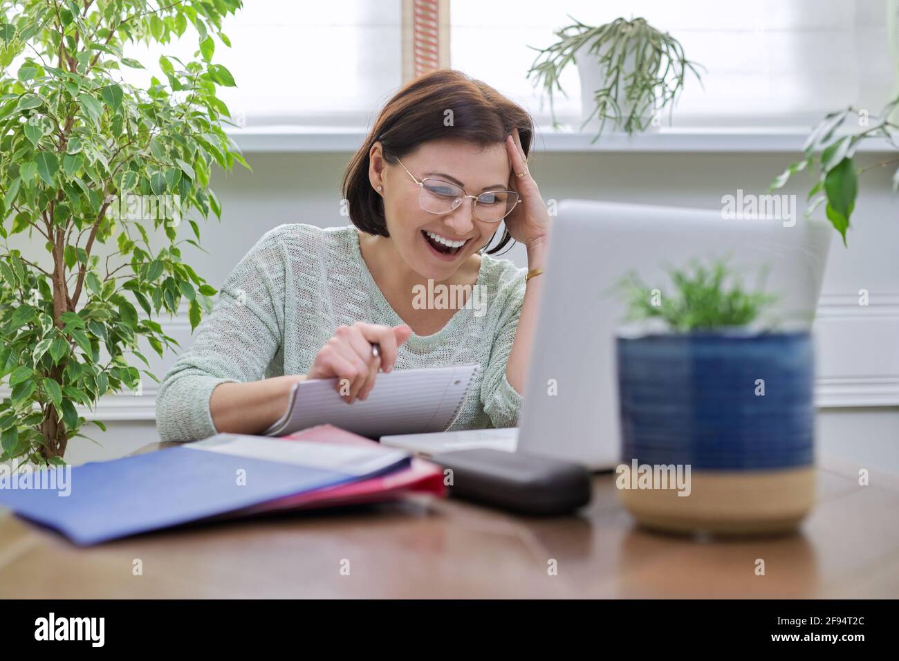 Female teacher teaching online, sitting at home at table with laptop ...