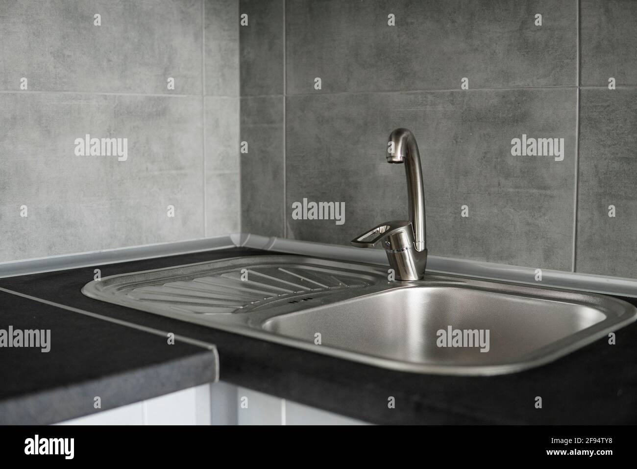 Stainless steel kitchen sink on a dark grey granite worktop. Kitchen ...