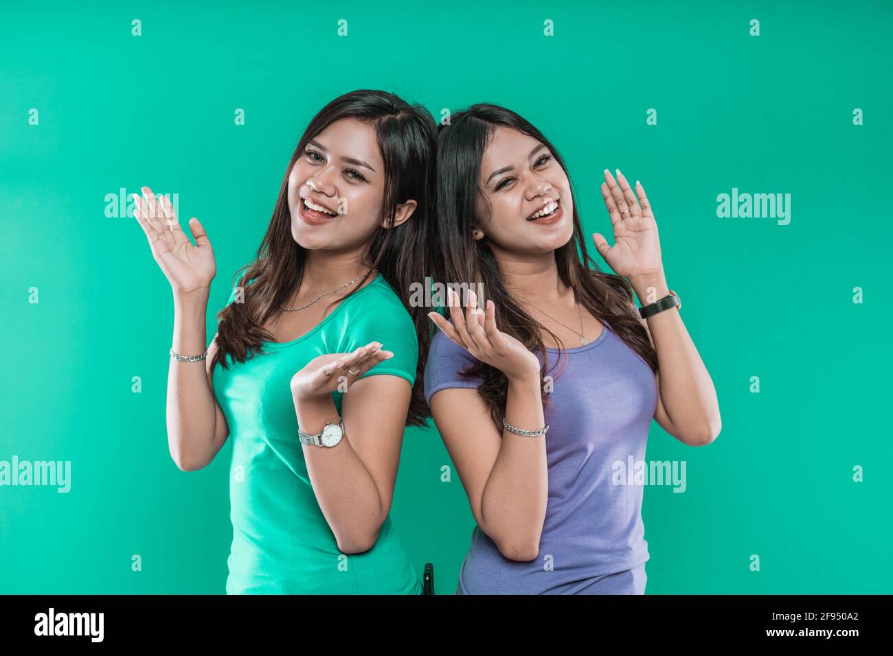 Portrait of beautiful young girls smiling together and waving at camera ...
