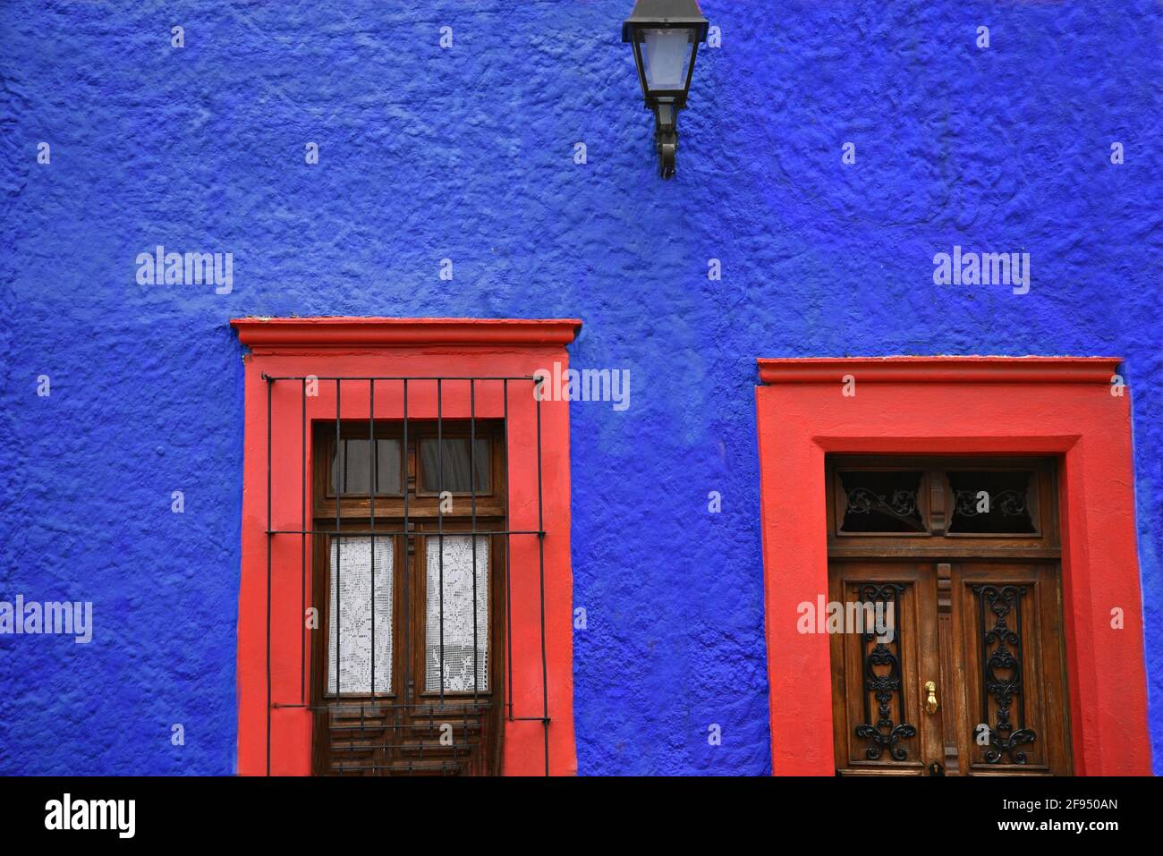 Colonial house facade with a cobalt blue textured wall and a scarlet ...