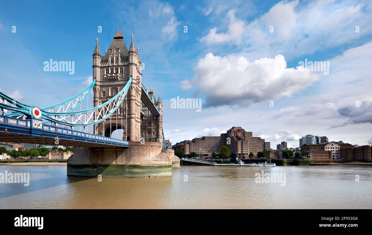 Tower Bridge on a bright sunny day with blue sky and clouds. Calm water ...