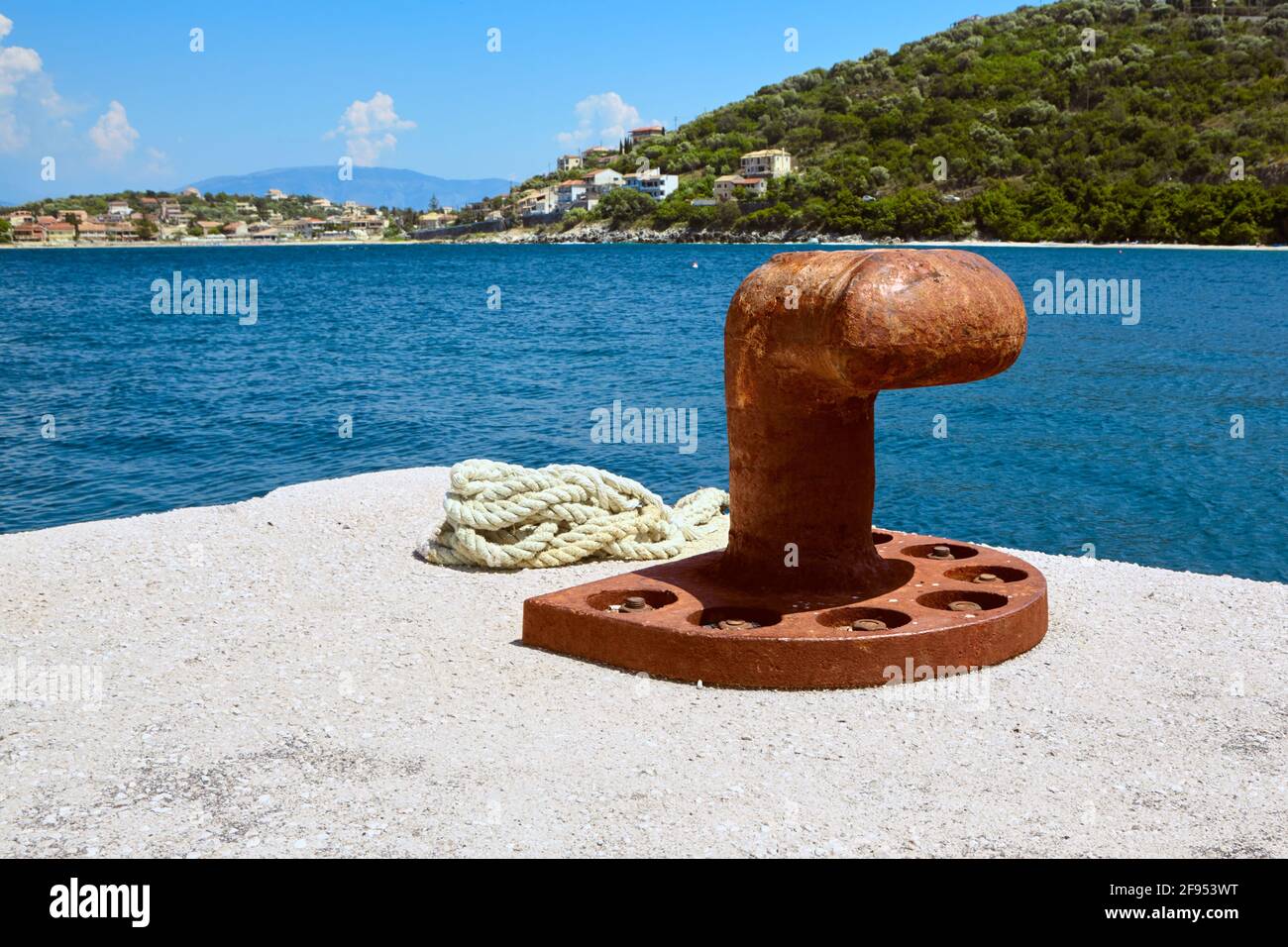 Old rusted mooring bollard with naval ropes on concrete pier. Greece ...