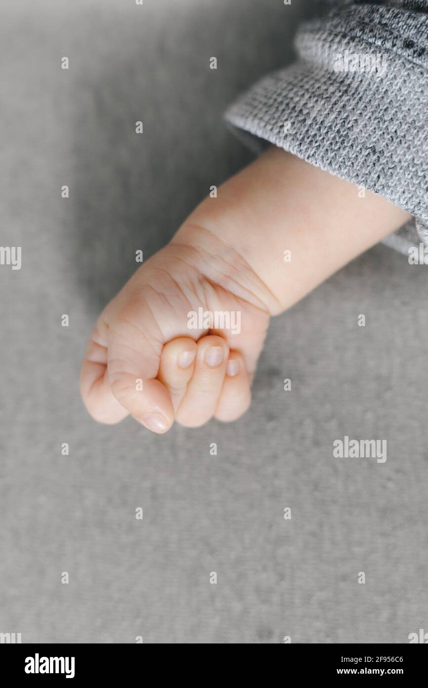 Hand of small newborn baby clenched into fist on gray background with ...