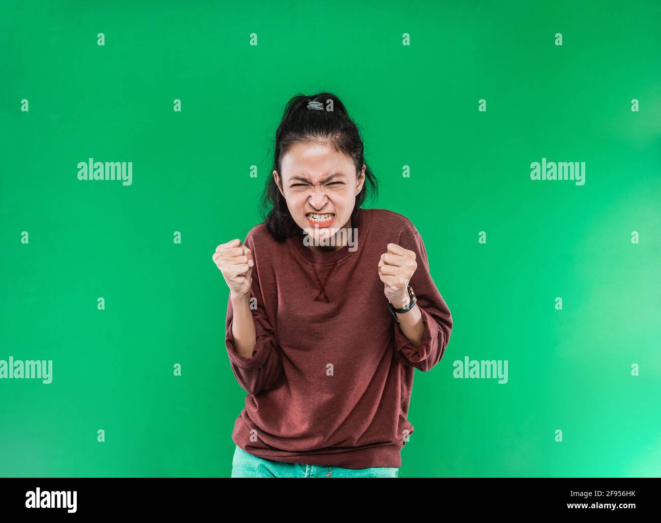 young Asian woman with angry expression the face while clenched into ...