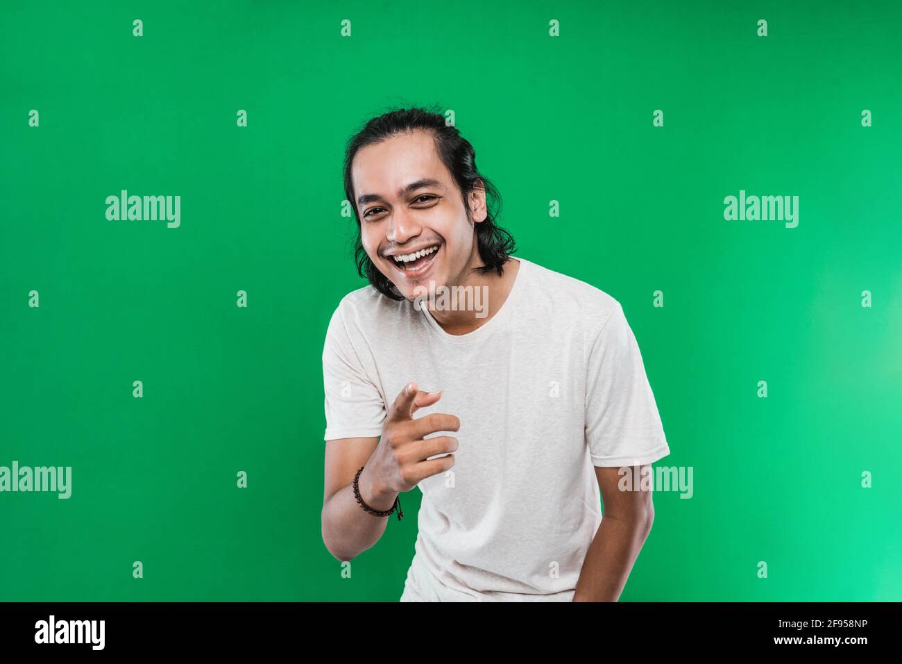 handsome man with long black hair Asian laughing happily while pointing ...