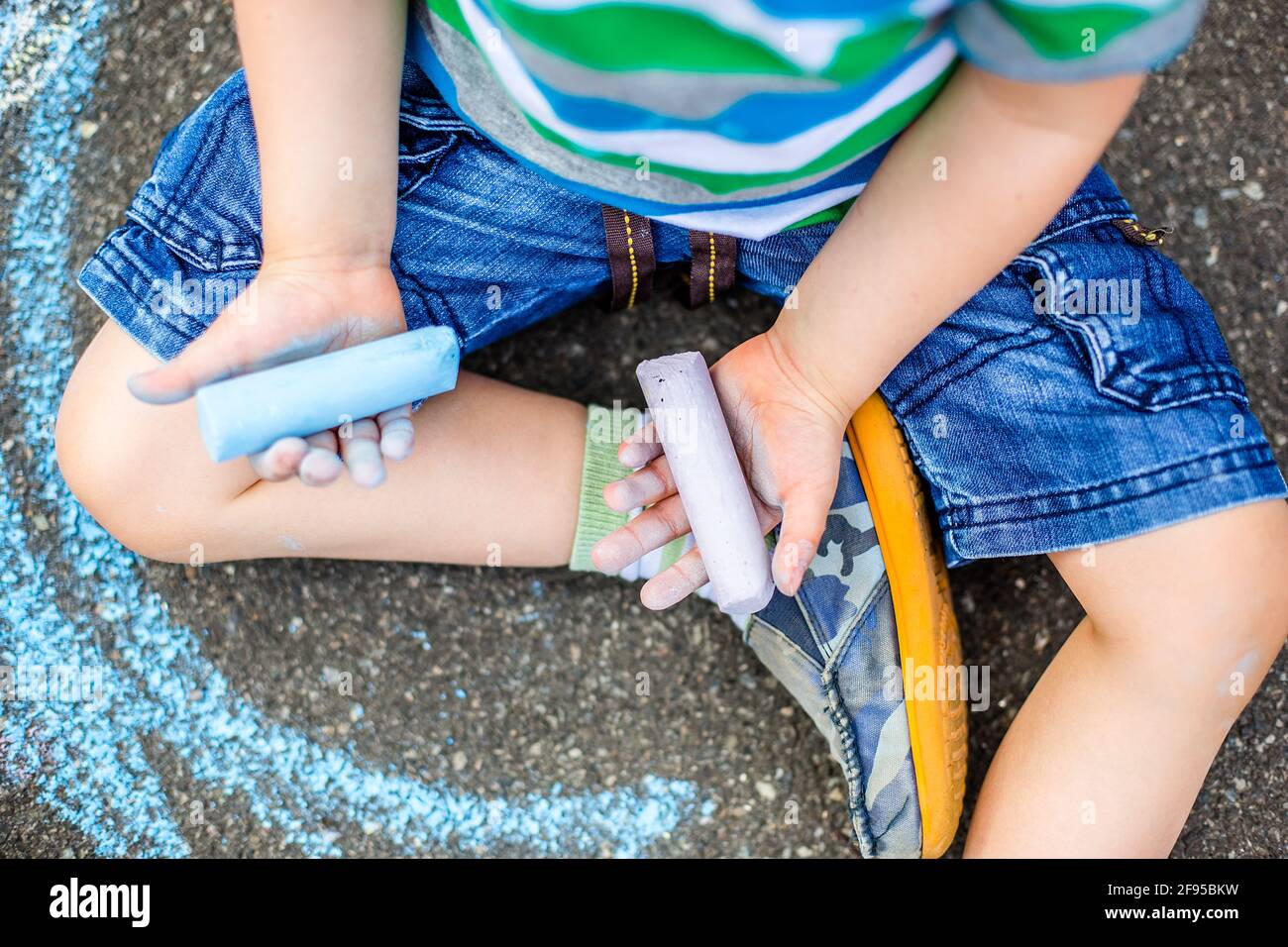 Cute boy and girl drawing with chalk on the sidewalk in the park ...