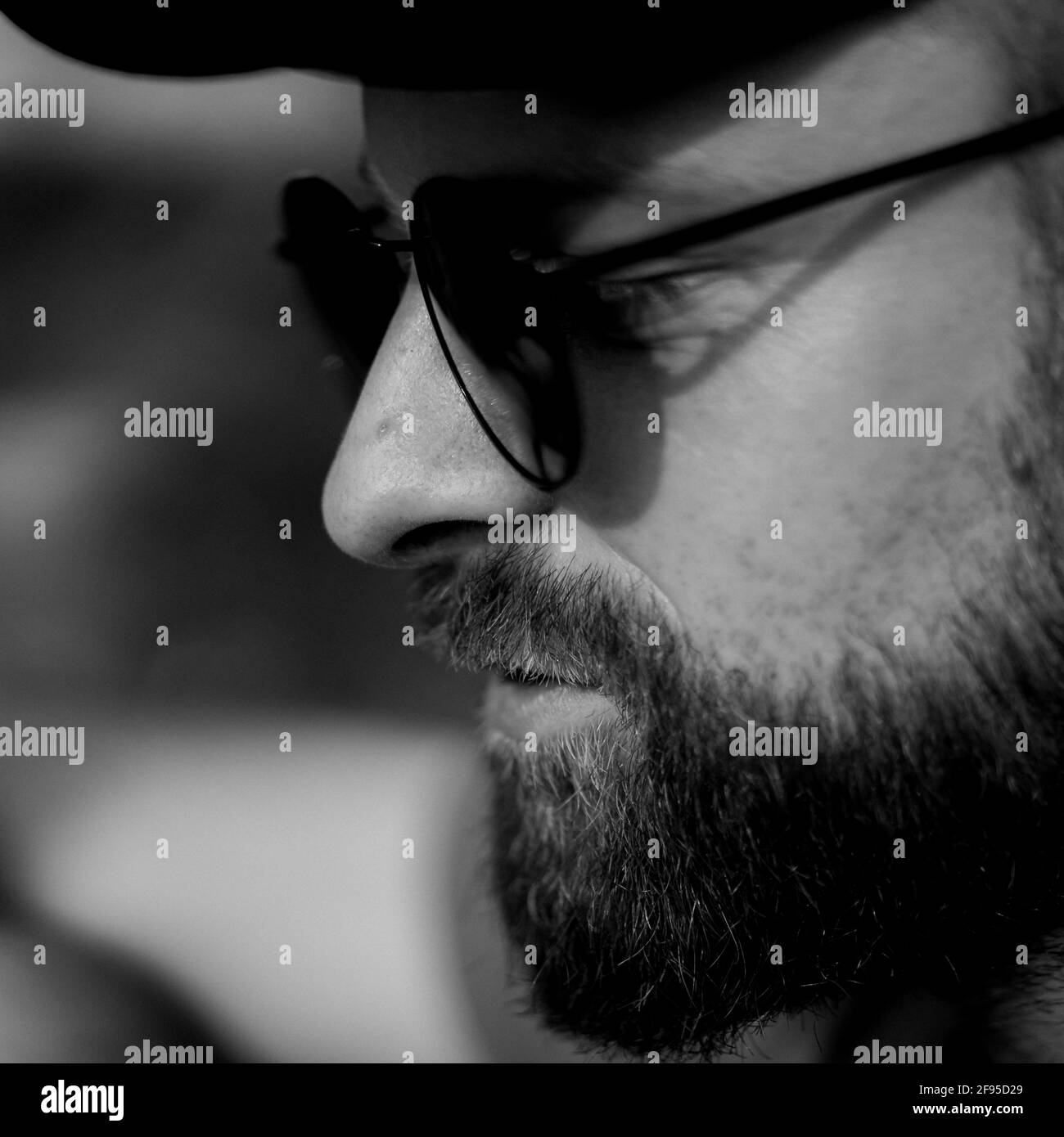 Vertical grayscale shot of a young Caucasian guy with a serious facial ...
