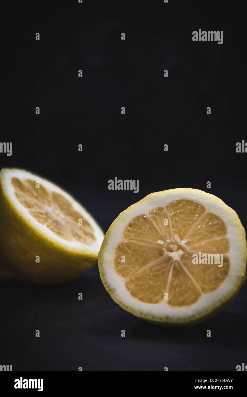 Lemon cut into two halfs, lying on dark background, vertical with copy ...