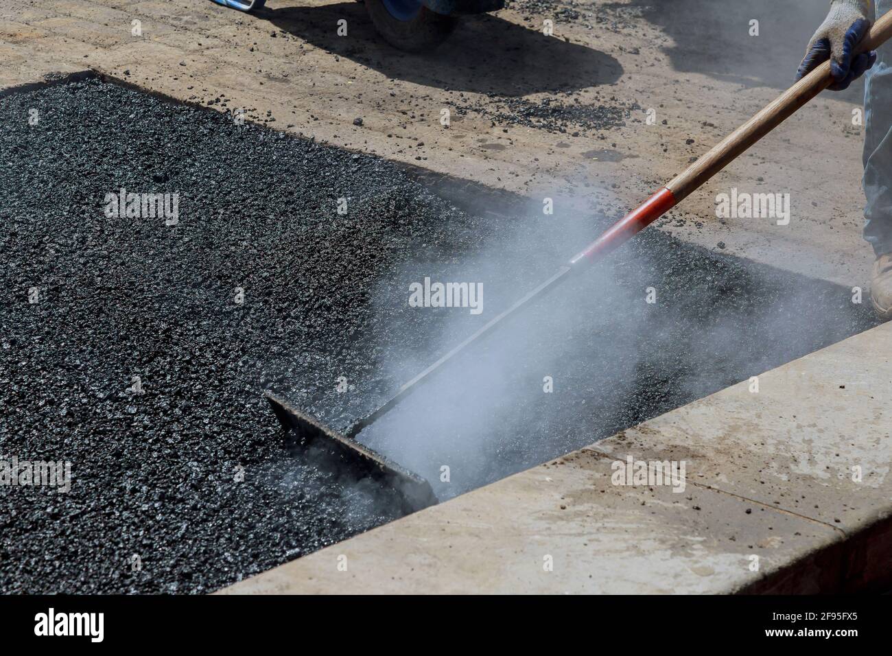 Worker repair asphalt covering while laying asphalt new road surface ...
