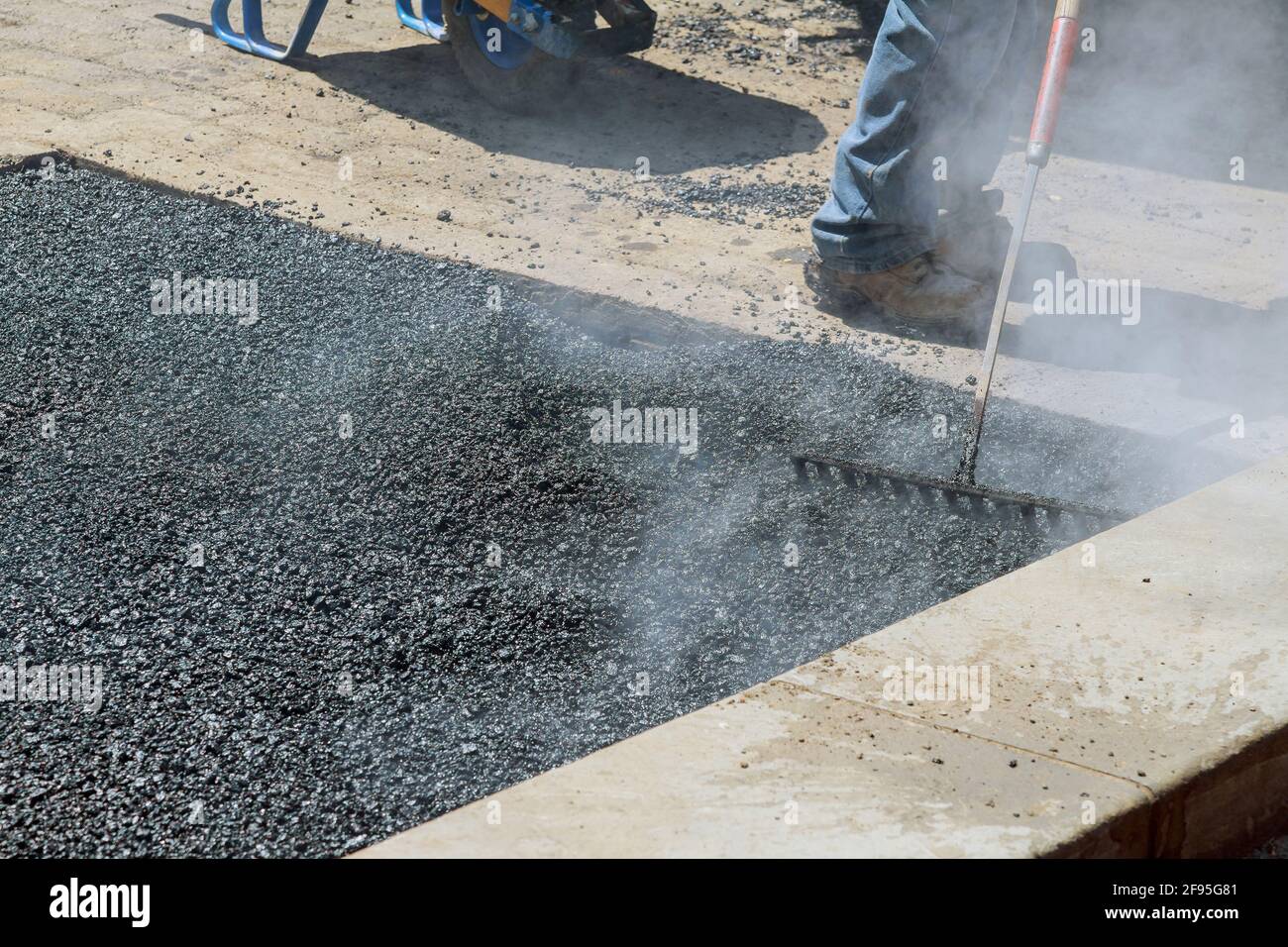 Man with a special tool takes a repair asphalt covering while laying ...