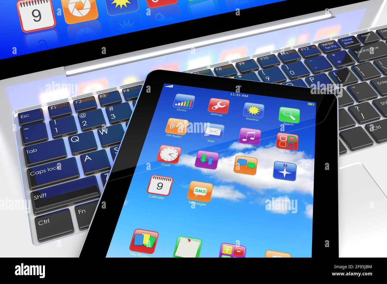 Tablet PC with colorful apps on a screen lying on laptop keyboard ...