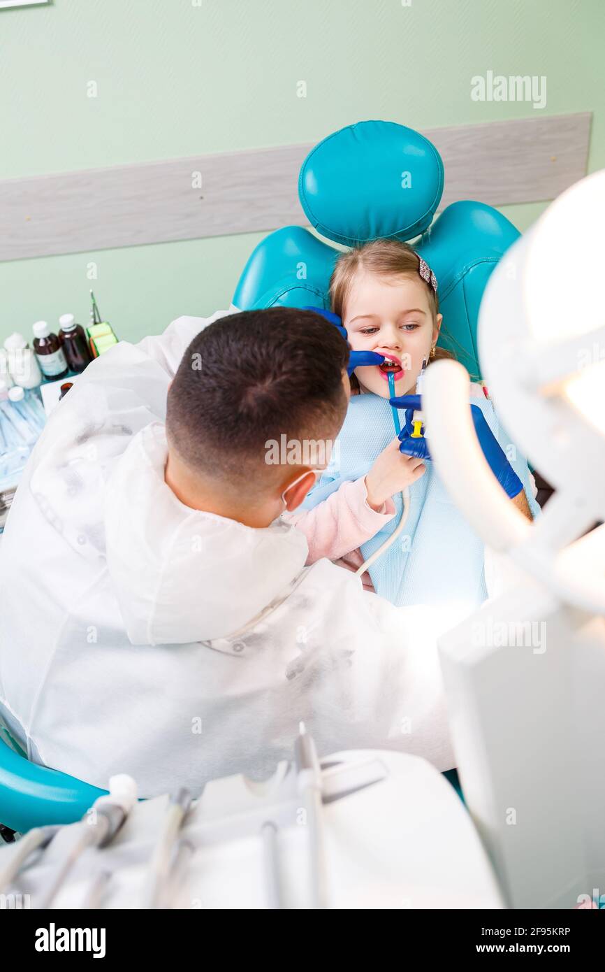 A professional doctor, a children's dentist, treats a little girl's ...