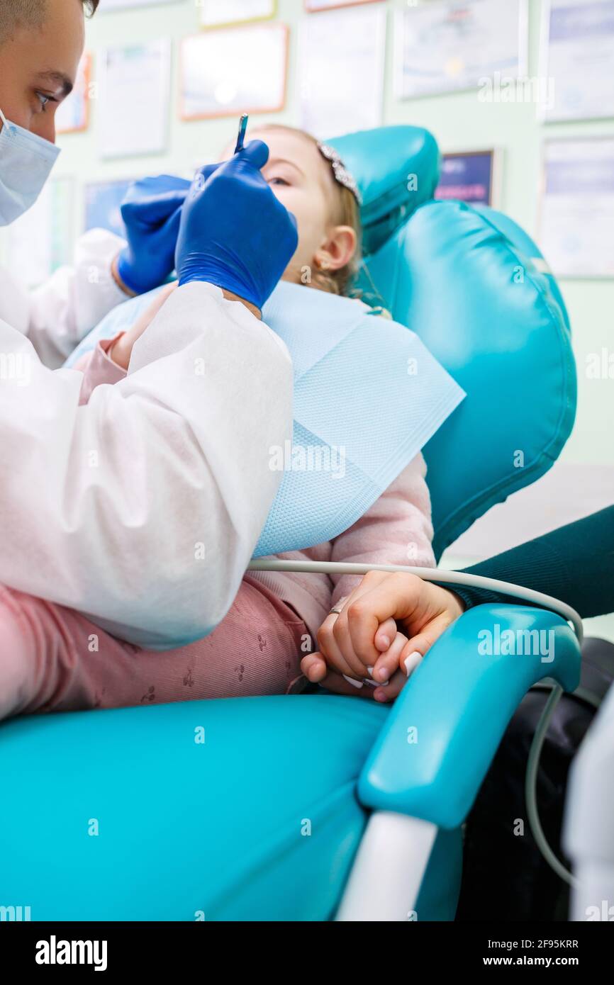 A professional doctor, a children's dentist, treats a little girl's ...