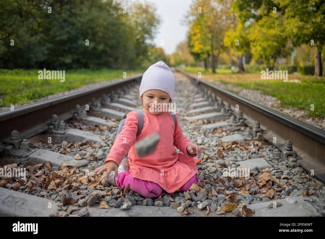 little girl sitting on the railroad tracks. toddler plays on railroad ...