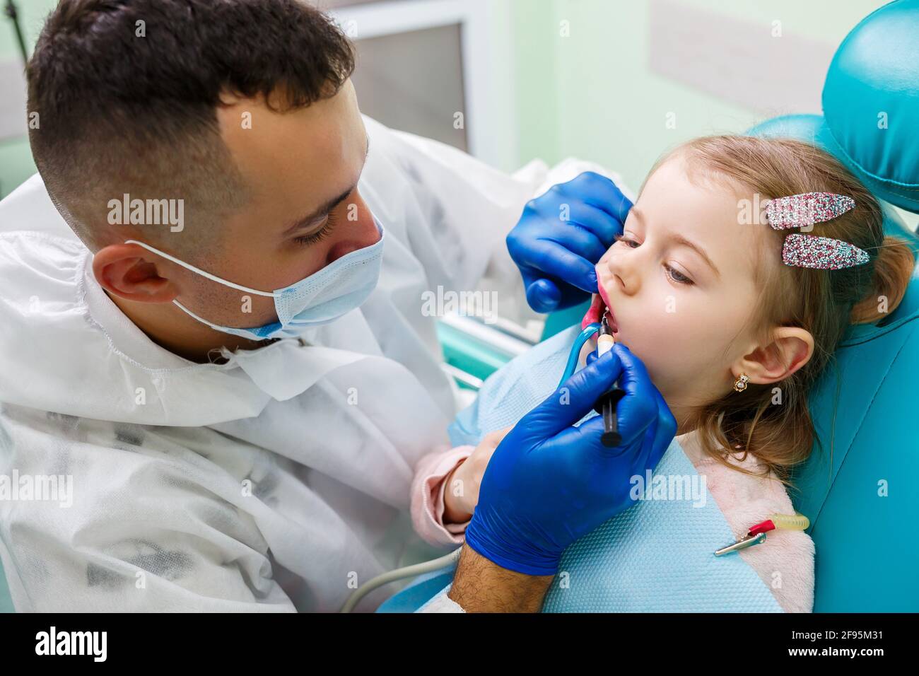 A professional doctor, a children's dentist, treats a little girl's ...