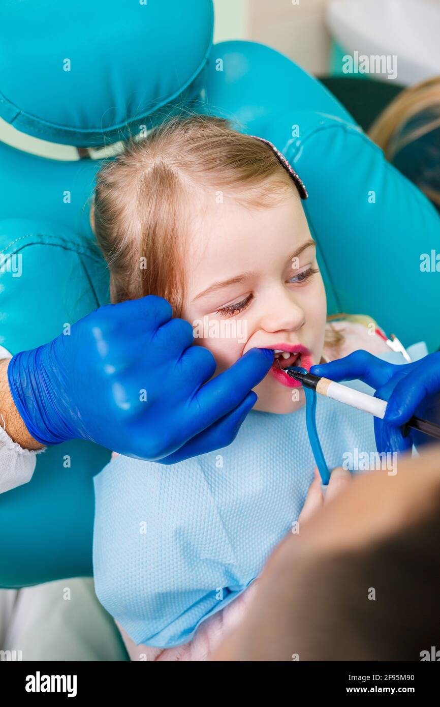 A professional doctor, a children's dentist, treats a little girl's ...