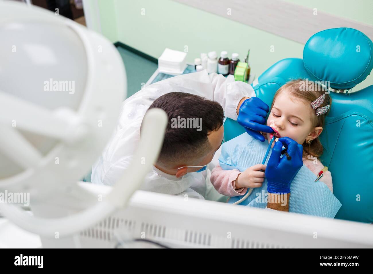 A professional doctor, a children's dentist, treats a little girl's ...