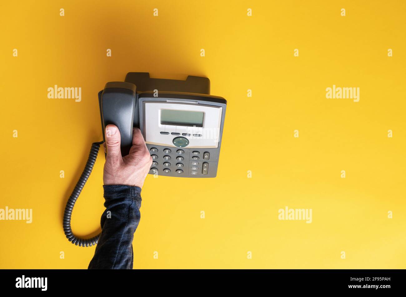 Top view of male hand picking up telephone receiver of a black landline ...