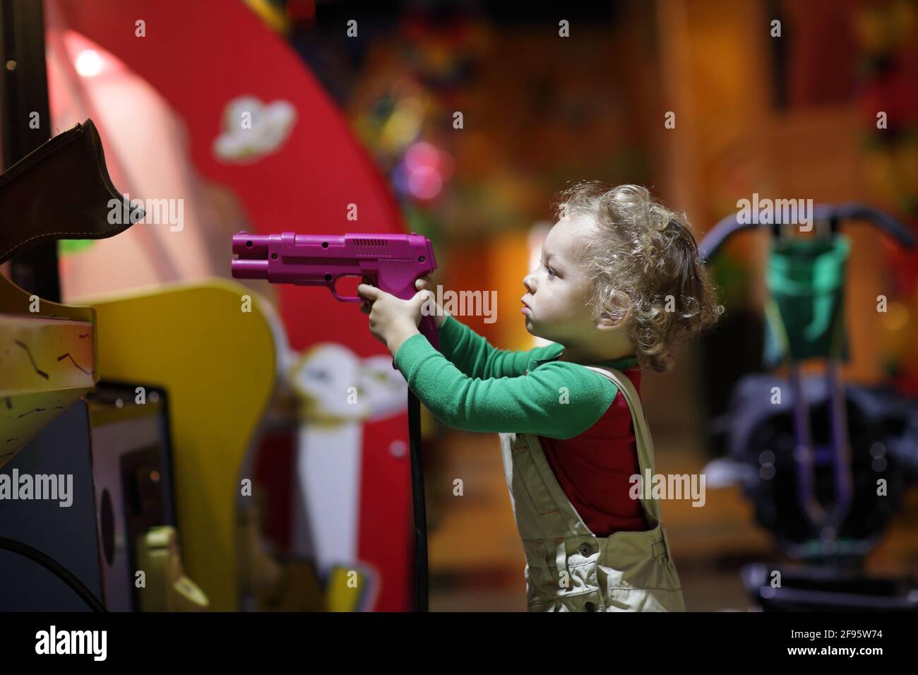 Child shooting a pistol at indoor playground Stock Photo - Alamy