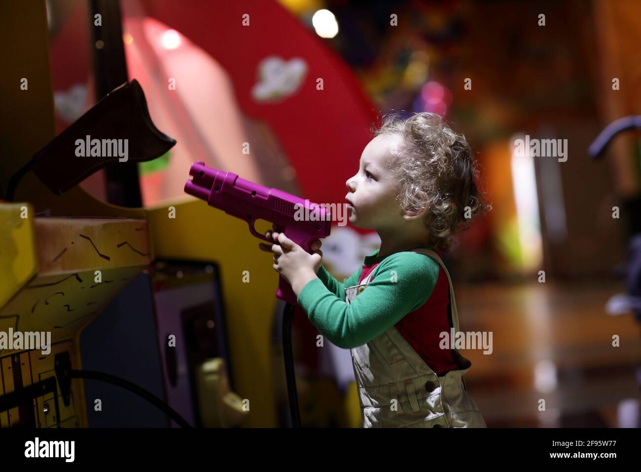 Child aiming a gun at indoor playground Stock Photo - Alamy