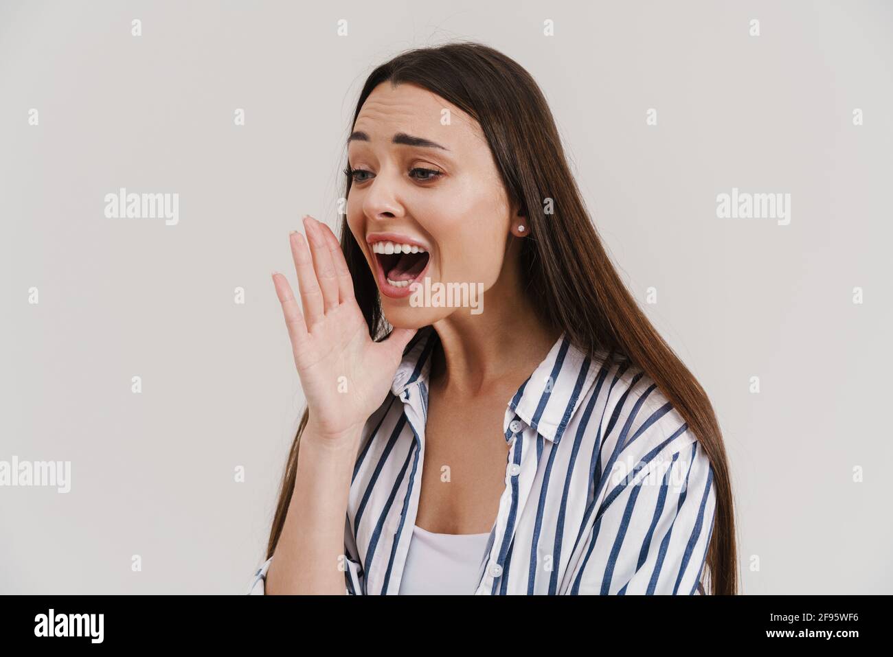 Excited beautiful brunette girl looking and screaming aside isolated ...