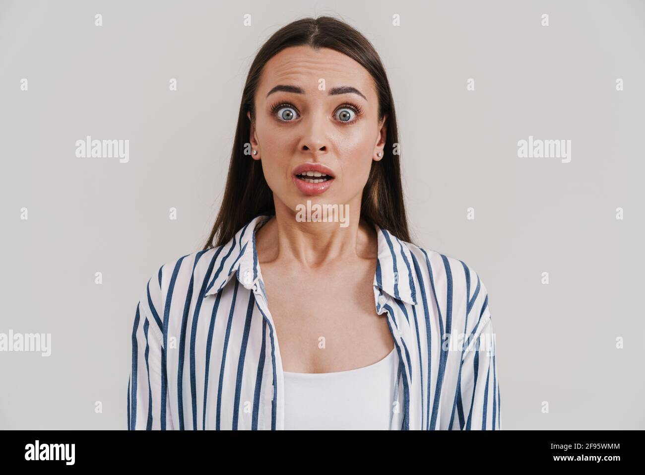 Shocked beautiful brunette girl expressing surprise at camera isolated ...