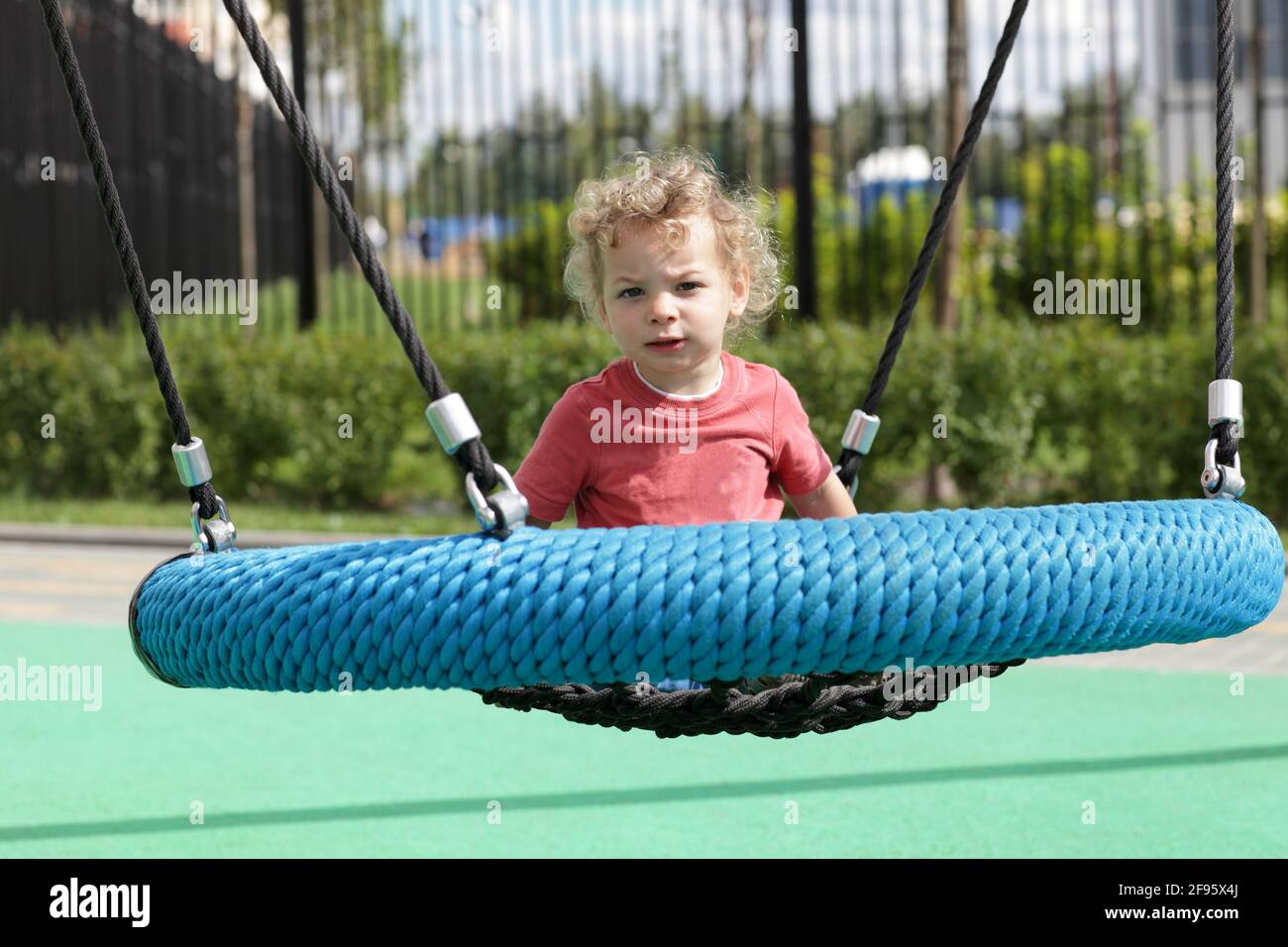 Curly child is playing at swing at playground Stock Photo - Alamy
