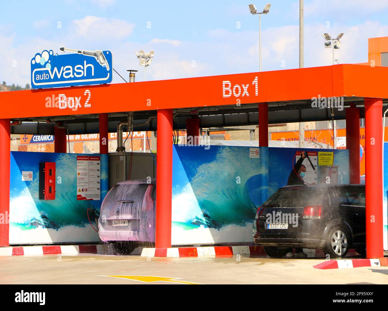 People using a hand car wash with power washers at a petrol station in ...